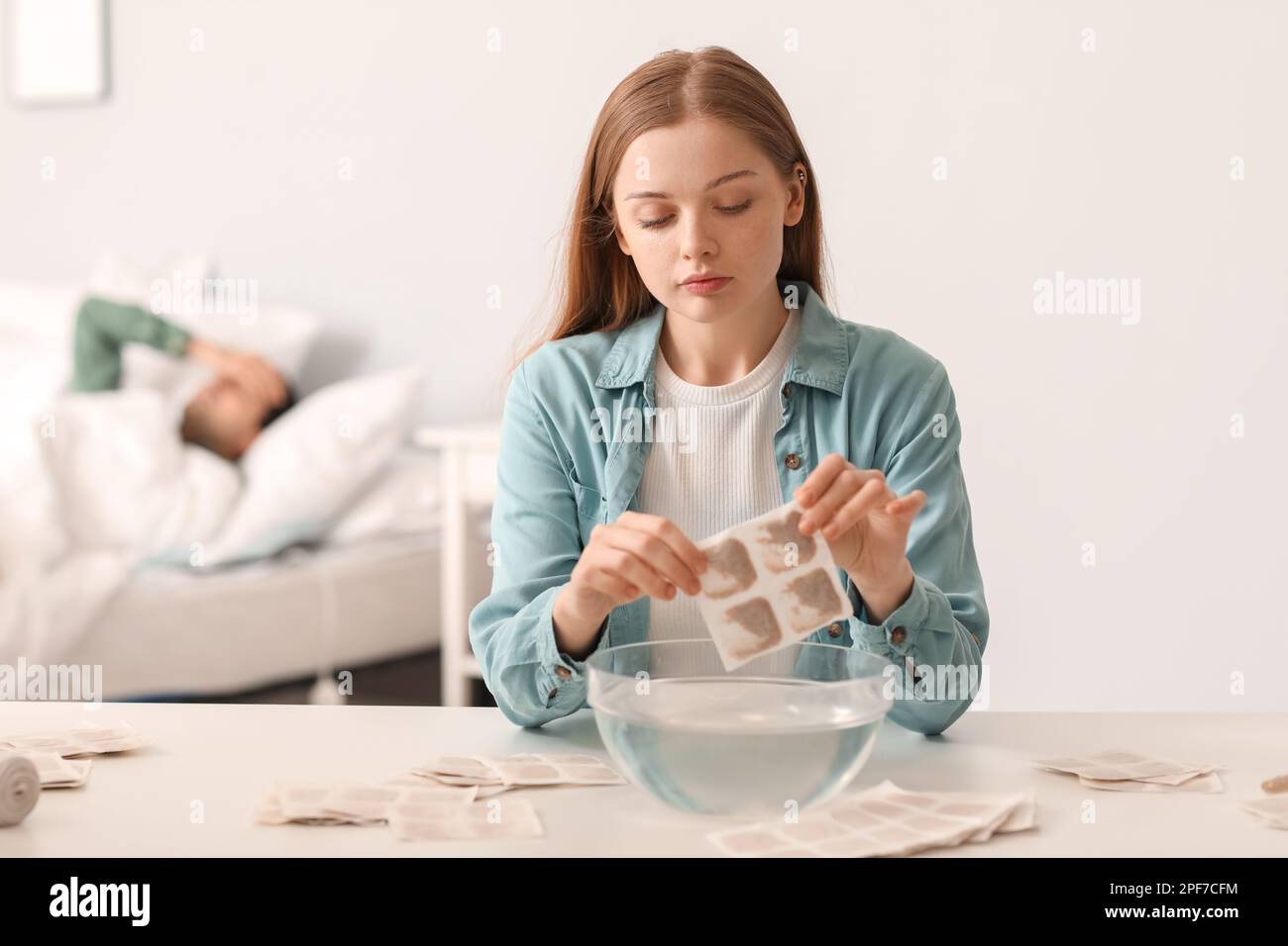 Young woman dipping mustard plaster into bowl of water in bedroom Stock ...