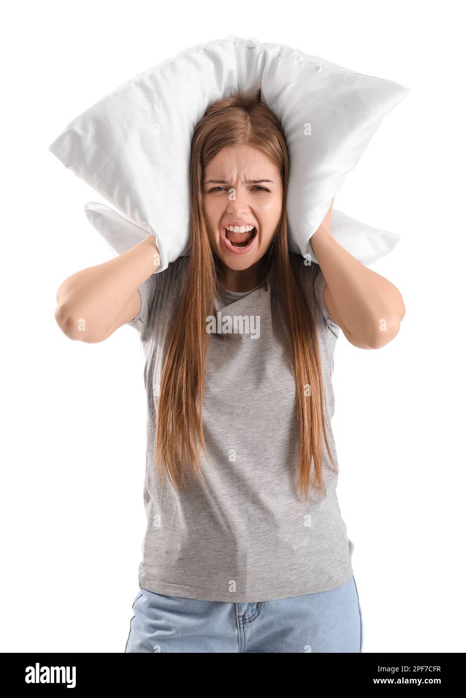 Irritated young woman with pillow suffering from loud noise on white ...