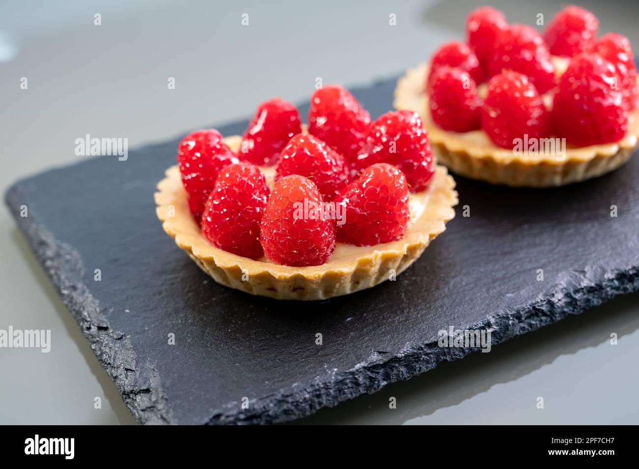 Artisanal baked small tart with cream and fresh ripe red raspberry ...