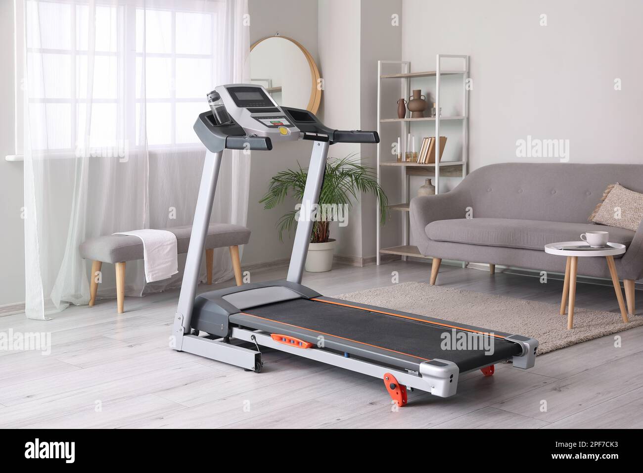Interior of light room with modern treadmill and sofa Stock Photo - Alamy