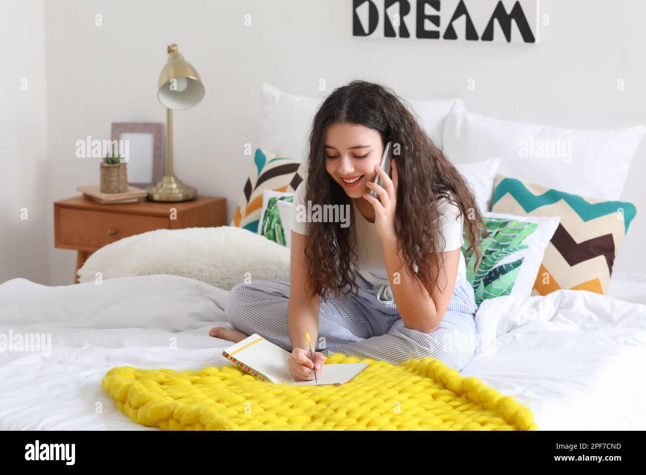 Teenage girl with notebook talking by mobile phone in bedroom Stock ...