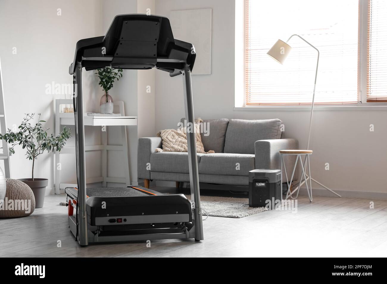 Interior of living room with portable power station, sofa and treadmill ...