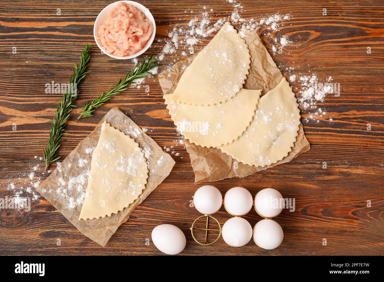 Raw empanadas, forcemeat, chicken eggs and rosemary on wooden ...