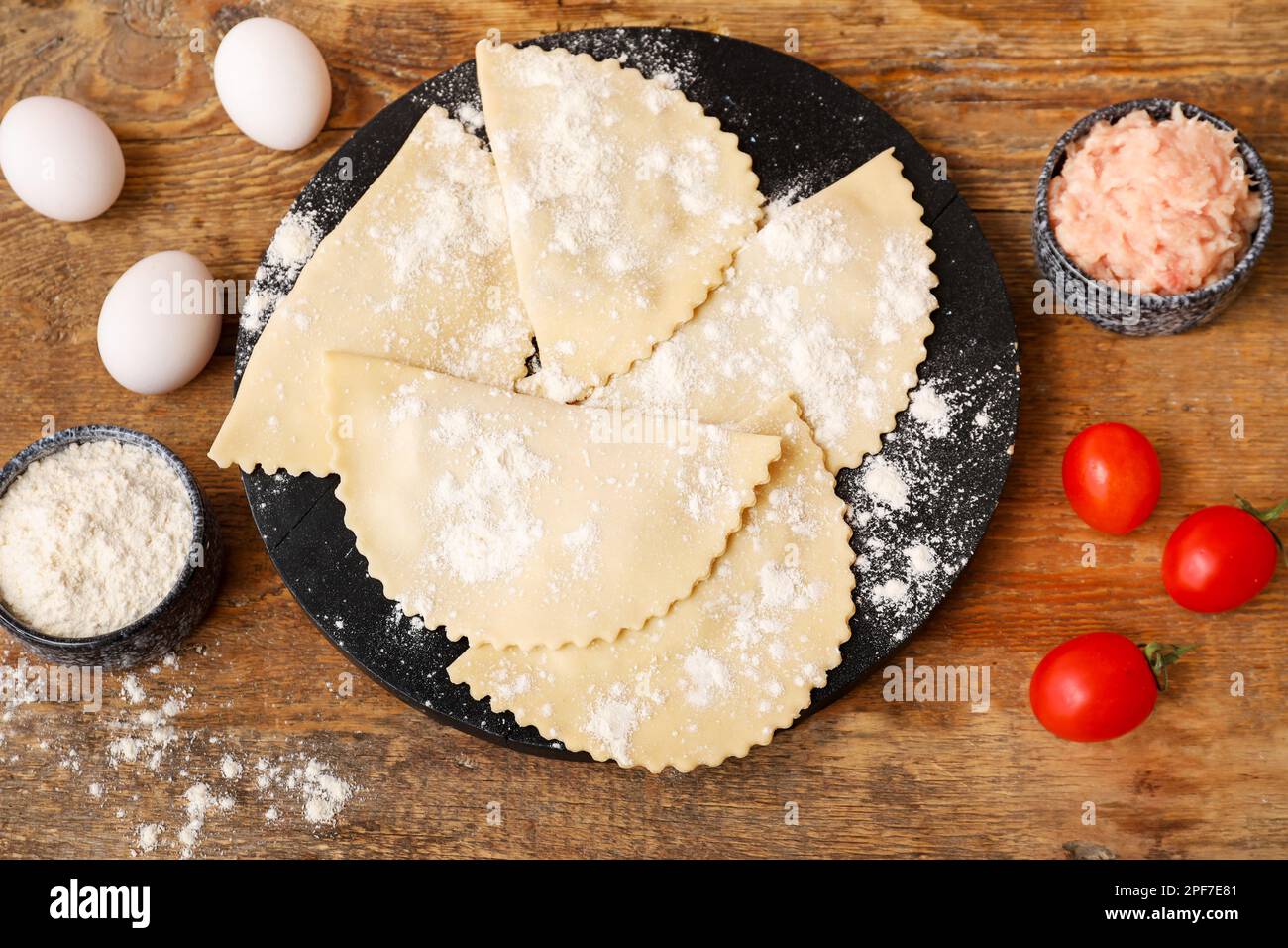 Board with raw empanadas, forcemeat, chicken eggs, flour and tomatoes ...