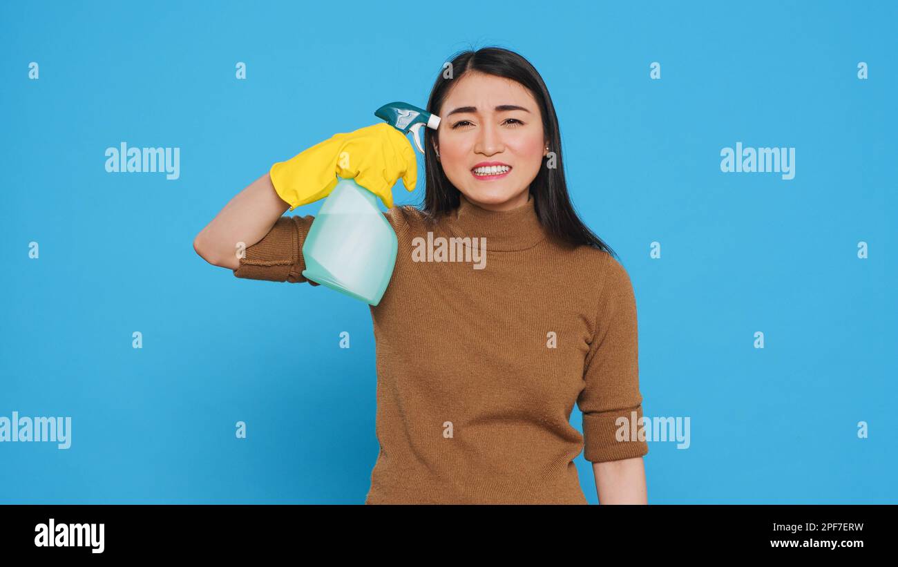 Upset angry maid putting detergent spray in front of temple while ...