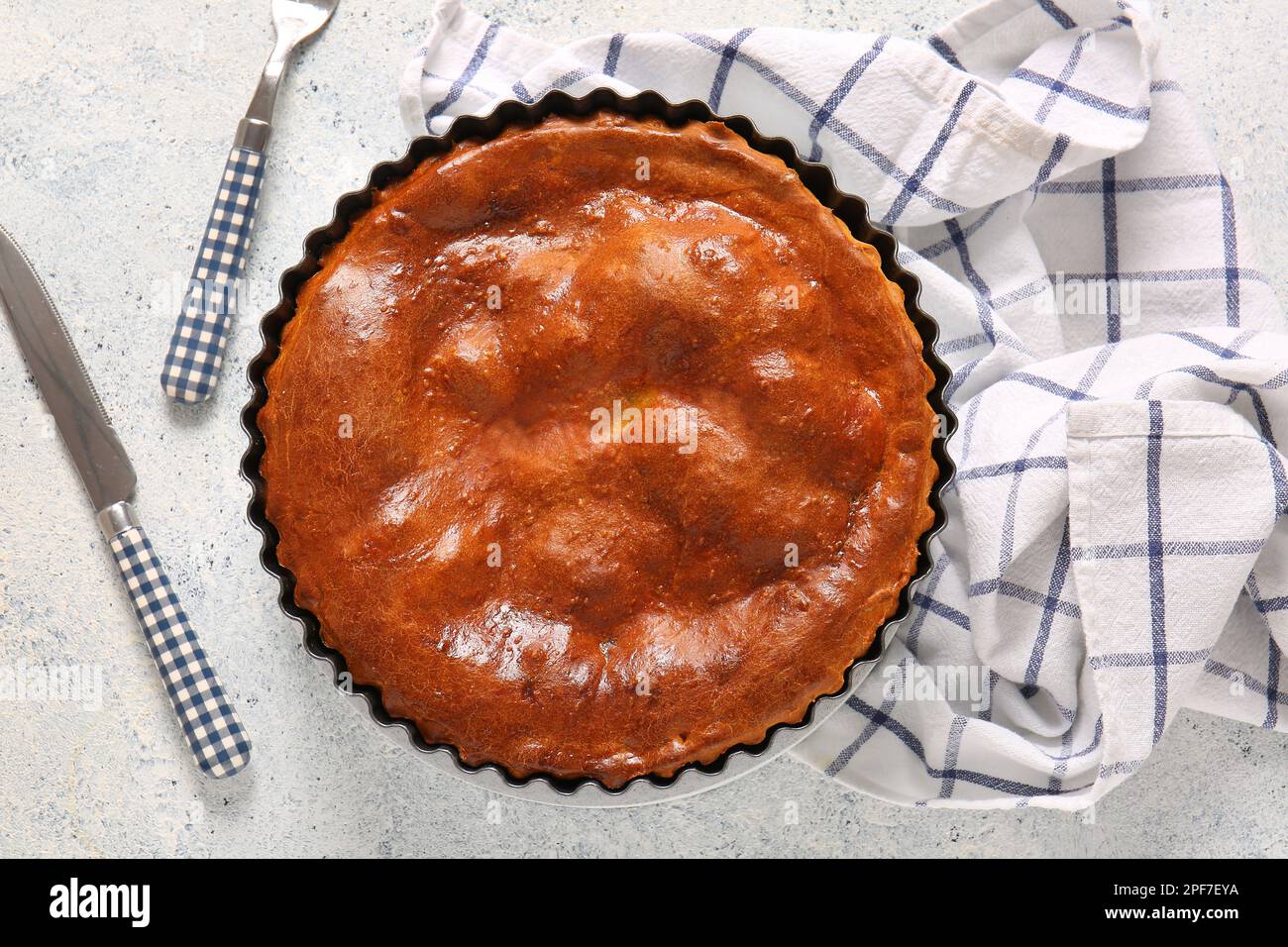 Delicious meat pie in baking form and cutlery on white grunge table ...