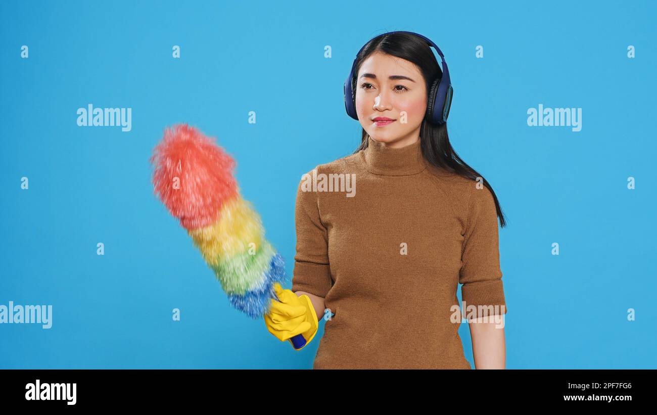 Cheeful housekeeper wearing headphones while dancing and having fun ...