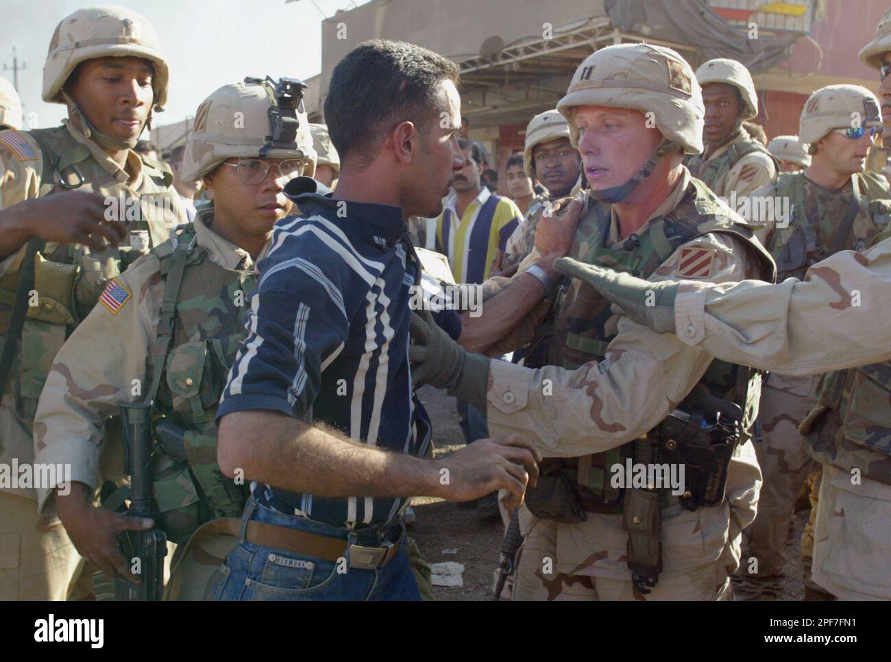 A US Army officer pushes off a man from a gas-oil separation plant ...