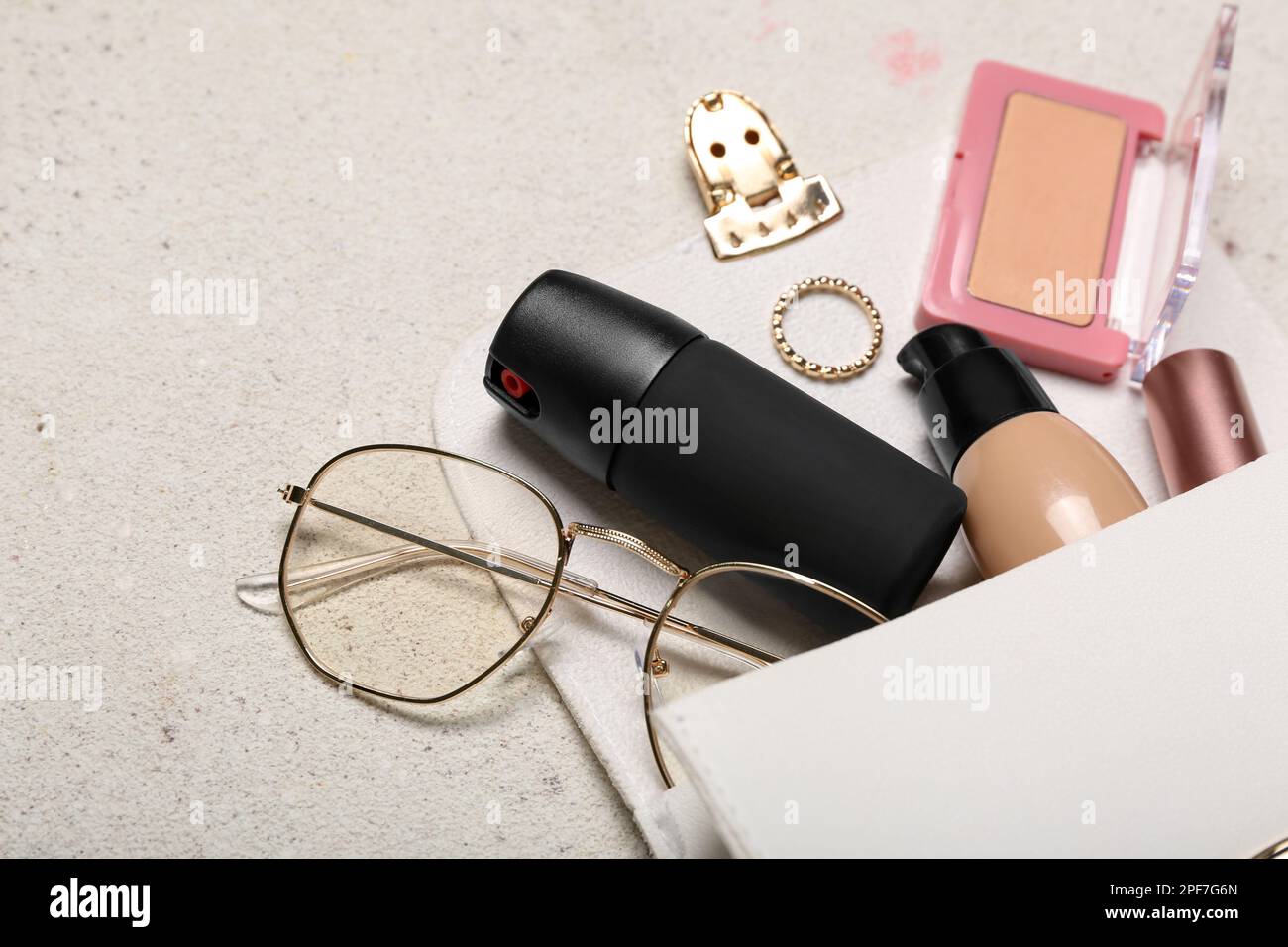 Bag with pepper spray and accessories on light background, closeup ...