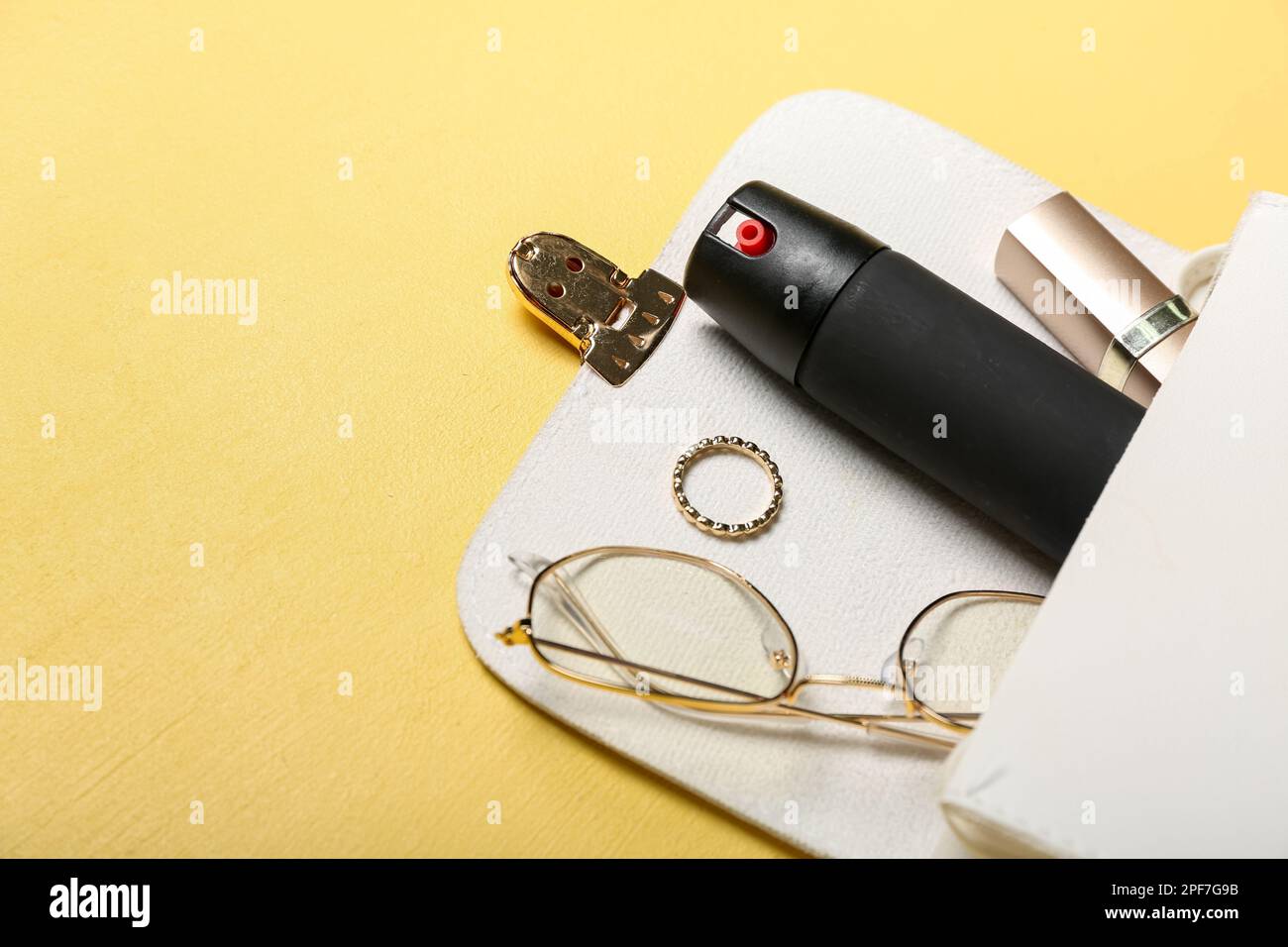 Bag with pepper spray and accessories on yellow background, closeup ...
