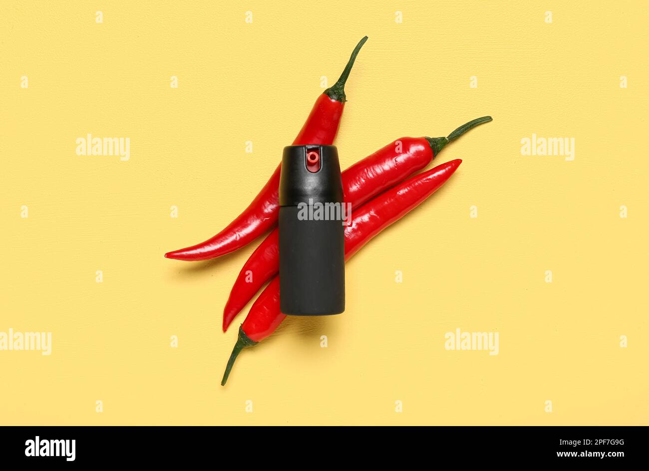Spray with chili peppers on yellow background Stock Photo - Alamy