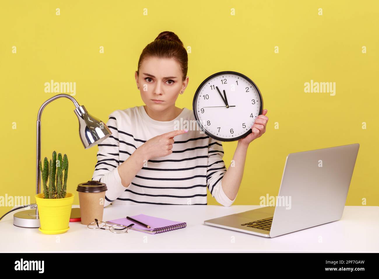 Serious bossy woman office worker pointing finger at big wall clock ...