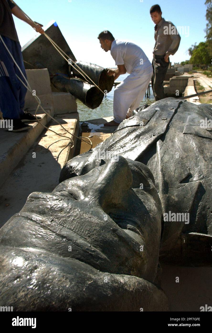 Iraqi men dismantle a statue of General Al Hayani, in Basra, Iraq ...