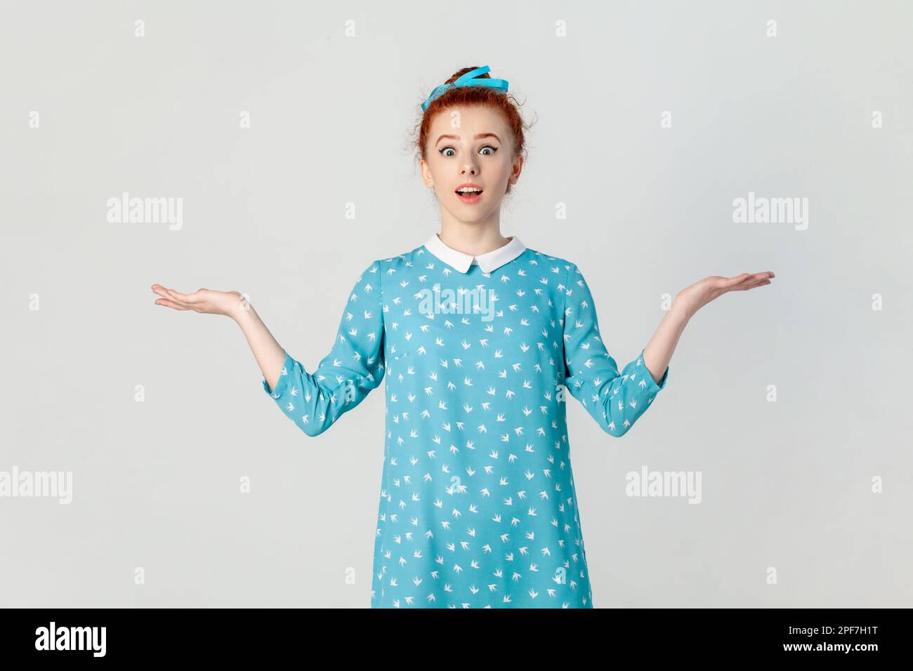 Portrait of shocked confused ginger woman standing with spread hands ...
