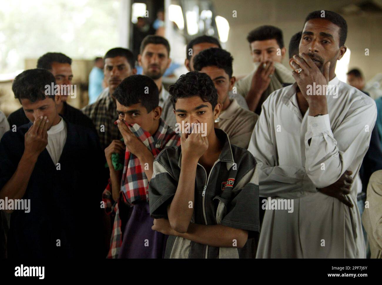 Iraqis cover their nose to avoid the smell as Iraqi civil defense ...