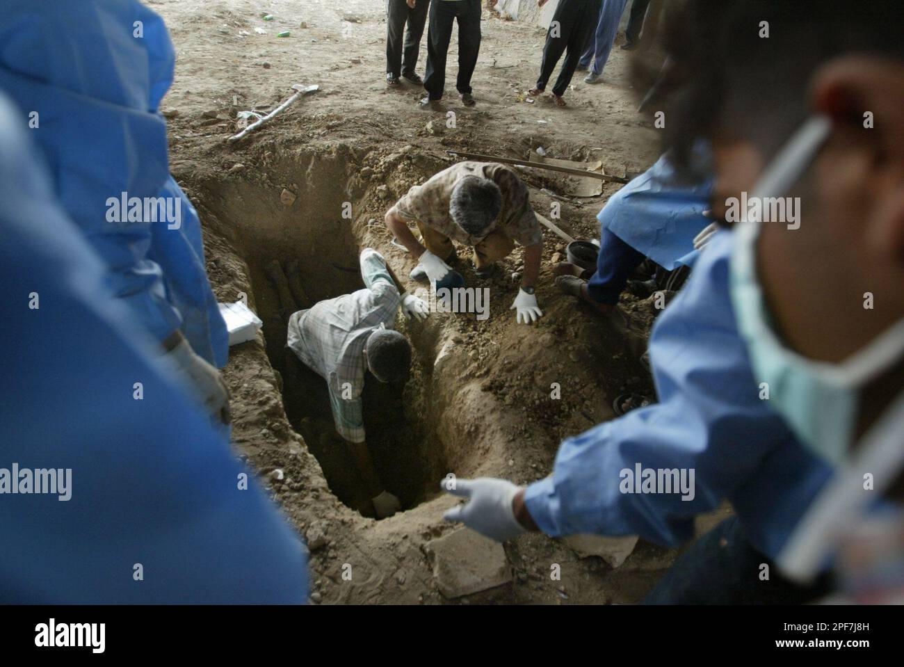 Iraqi civil defense workers unearth a body identified as an Iraqi ...