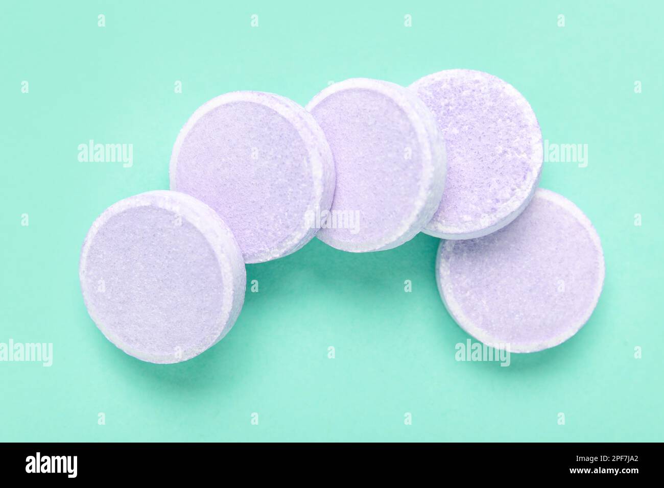 Lilac soluble tablets on turquoise background Stock Photo - Alamy