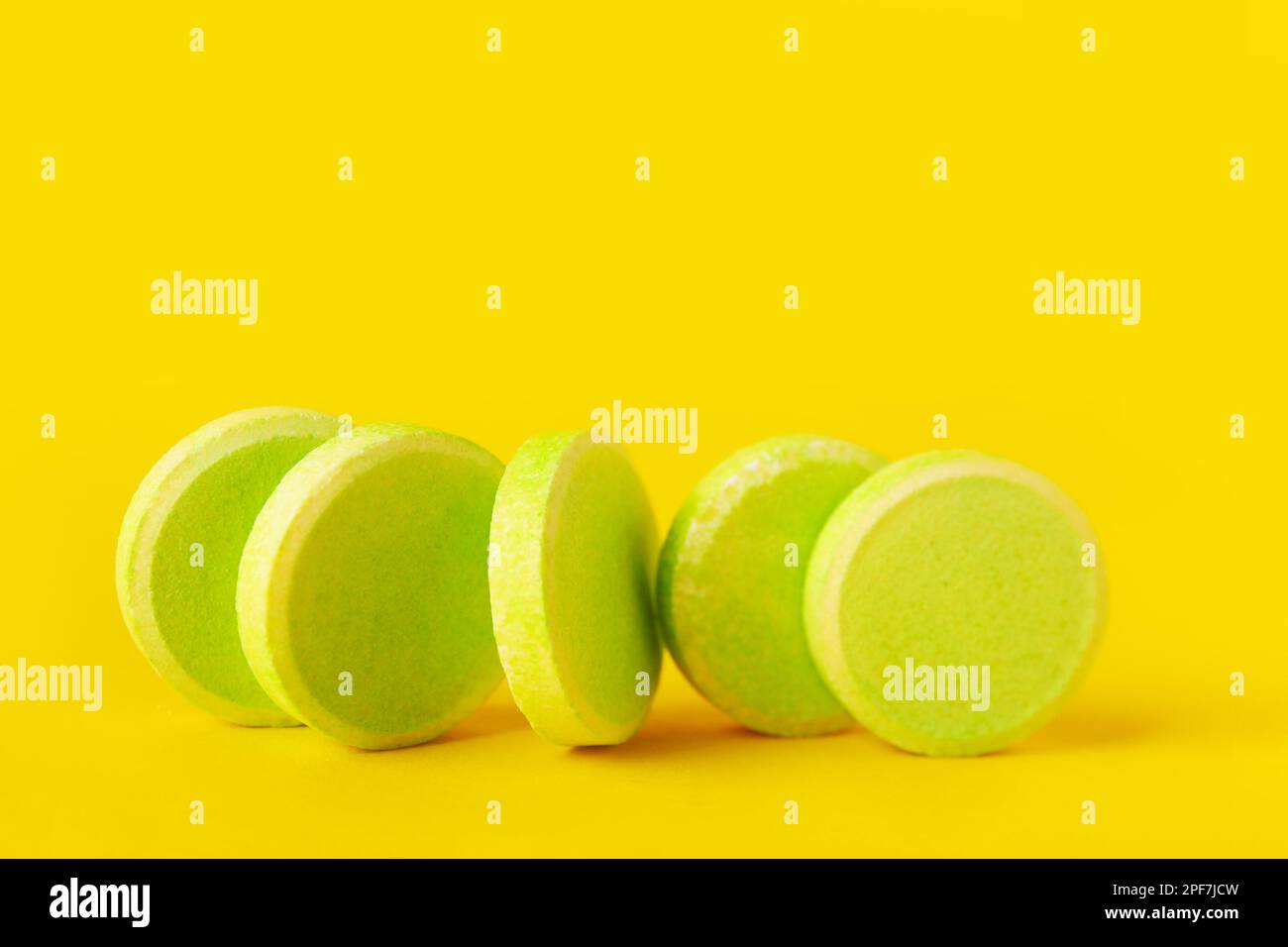 Green soluble tablets on yellow background Stock Photo - Alamy