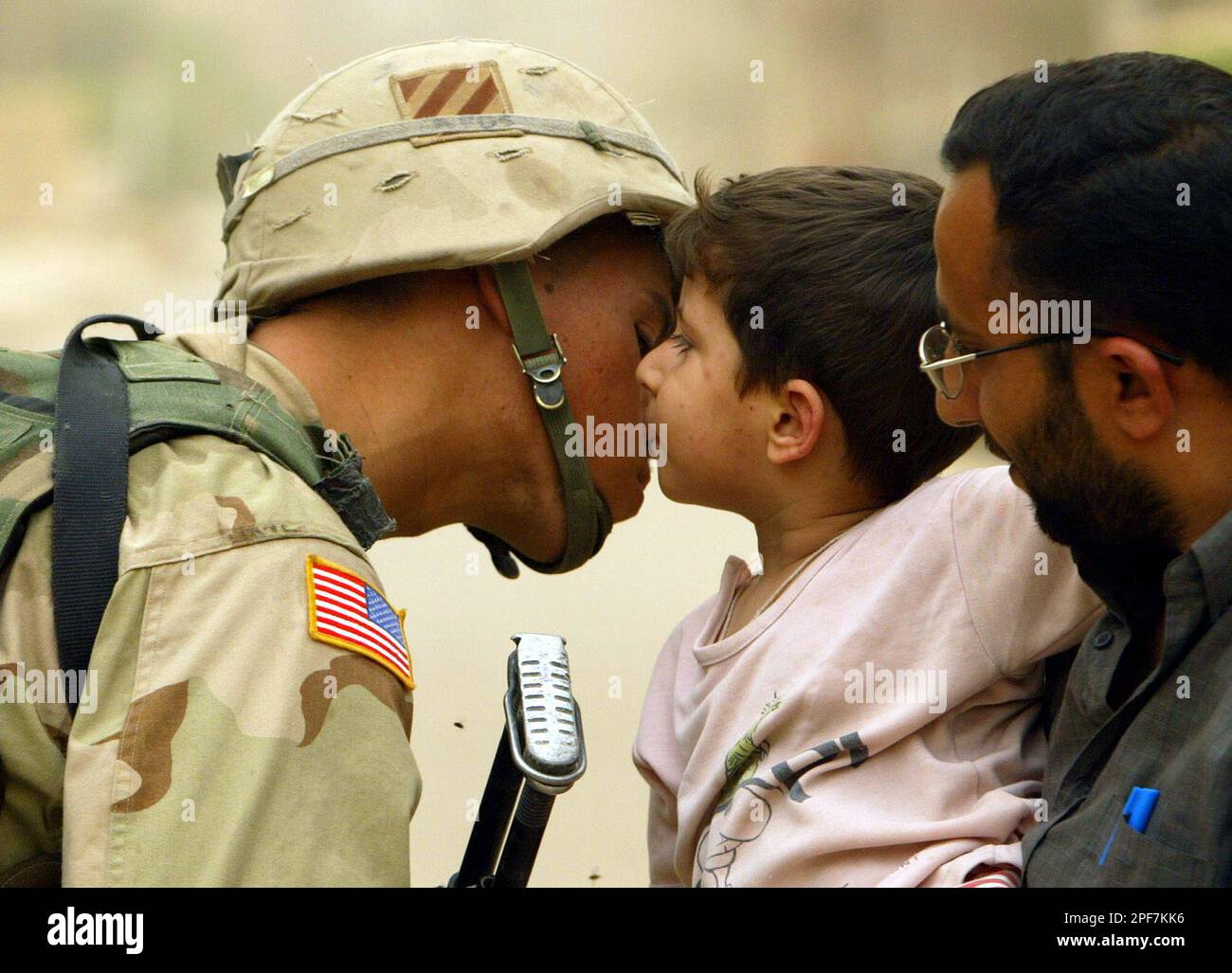 An Iraqi girl gives a kiss to U.S. soldier PFC Louis Livargas, of ...