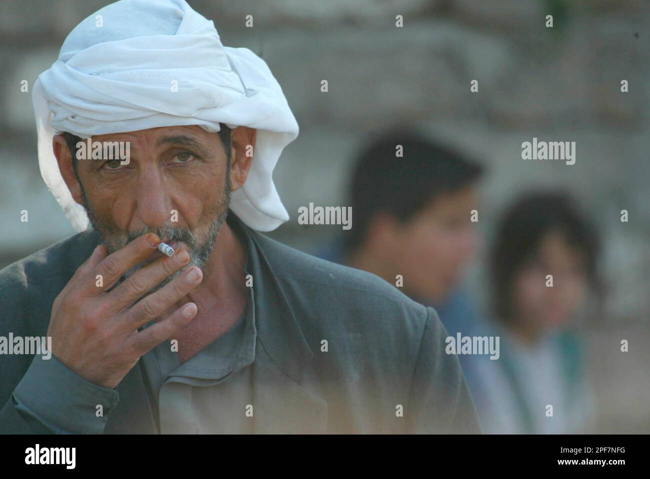An Iraqi man smokes a cigarette given to him by a US soldier in Mosul ...