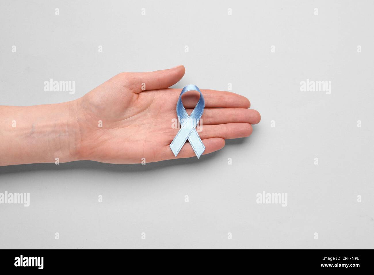Female hand with blue awareness ribbon on white background. Prostate ...