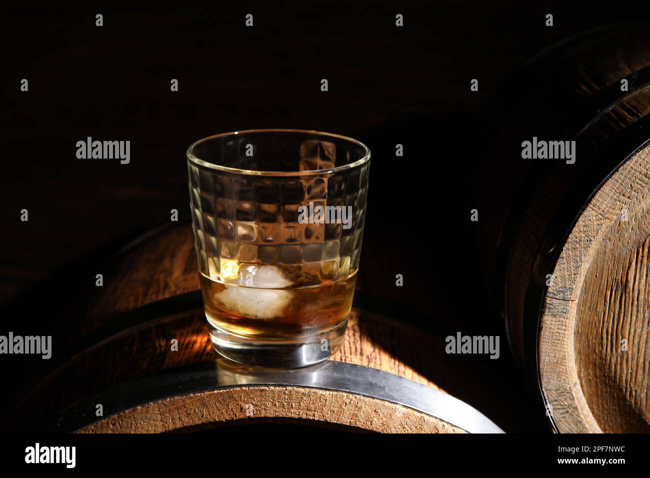 Glass of cold whiskey with wooden barrels on dark background Stock ...