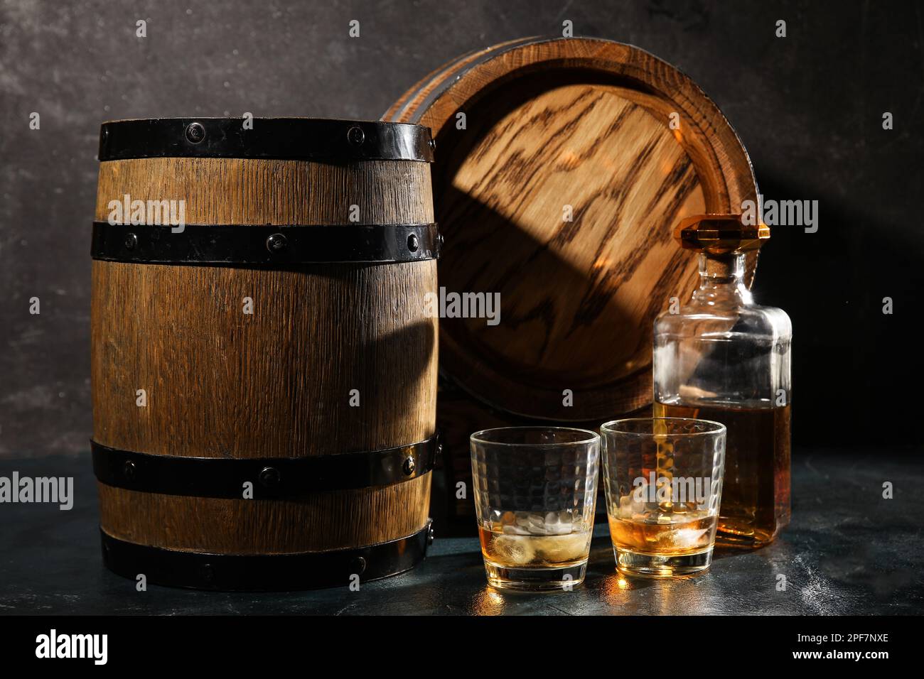Wooden barrels, bottle and glasses of cold whiskey on dark background ...