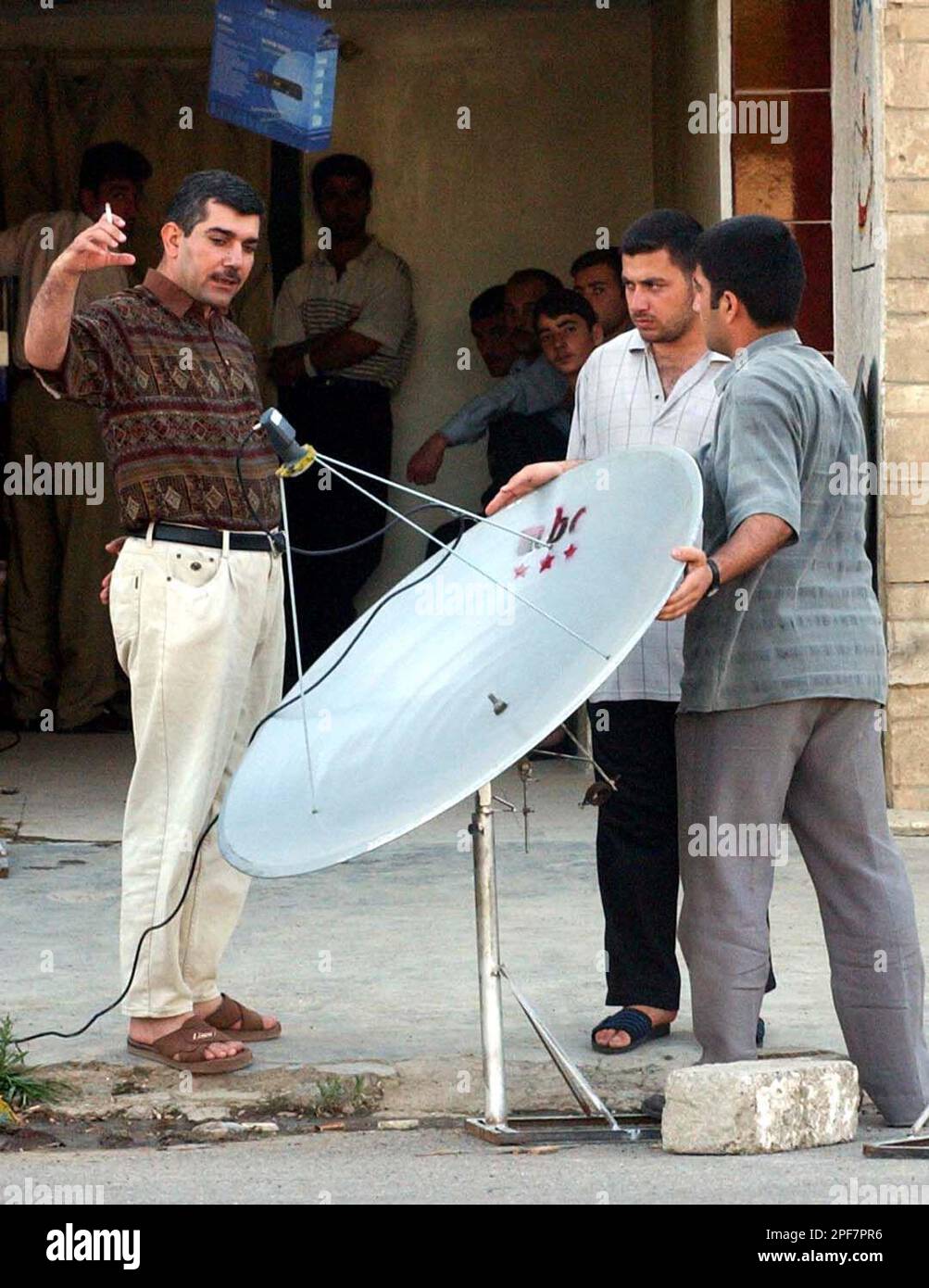 Iraqi Arab youth set up a satellite dish placed outside a shop in the ...