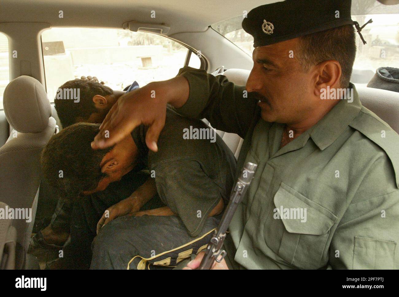 An Iraqi police officer smacks arrested Iraqi youths suspected of ...