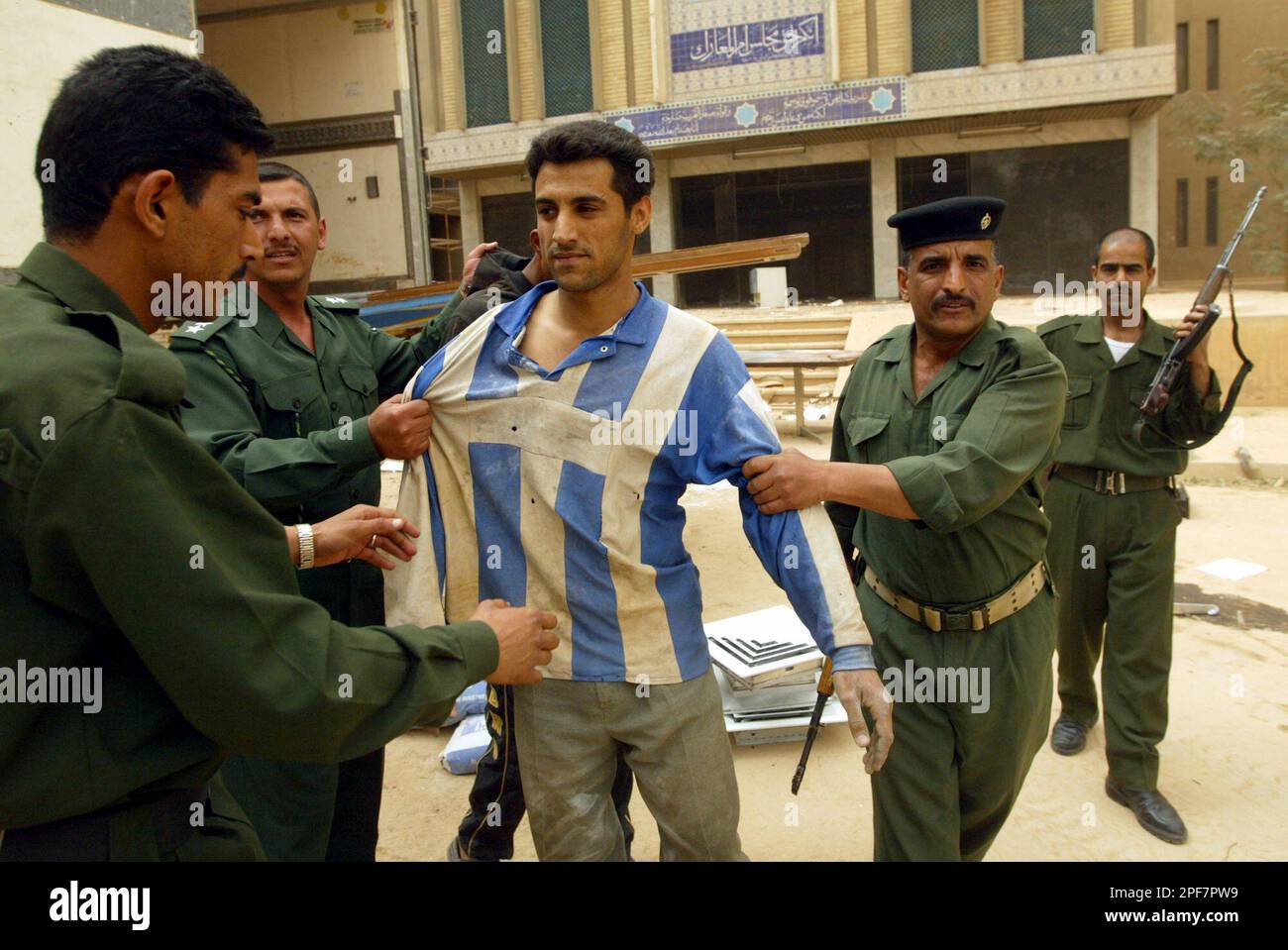 Iraqi Police officers arrest a looter at the National Assembly compound ...