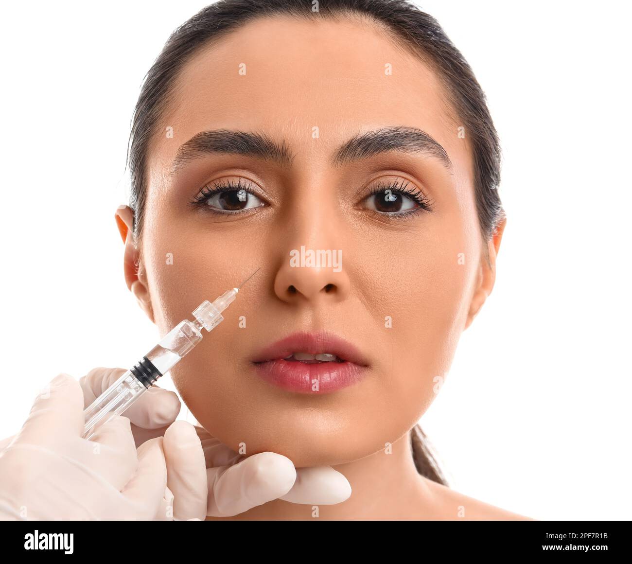 Young woman receiving filler injection in face against white background ...