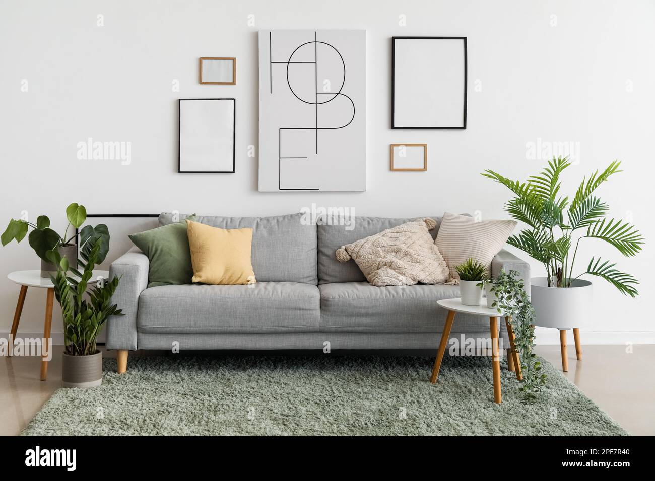 Interior of living room with cozy sofa, paintings and houseplants Stock ...