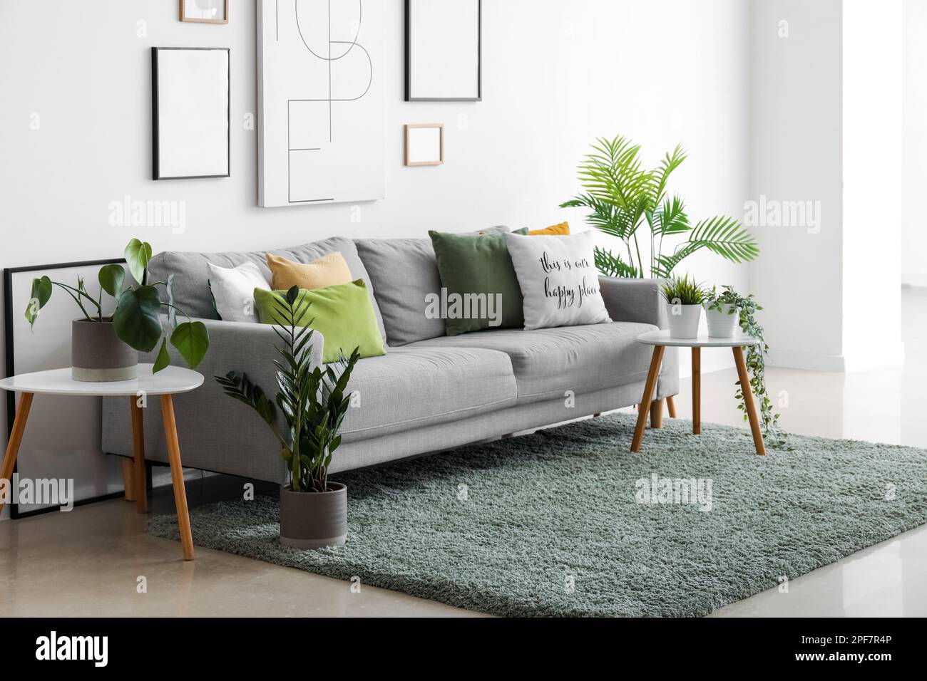 Interior of living room with cozy sofa, paintings and houseplants Stock ...