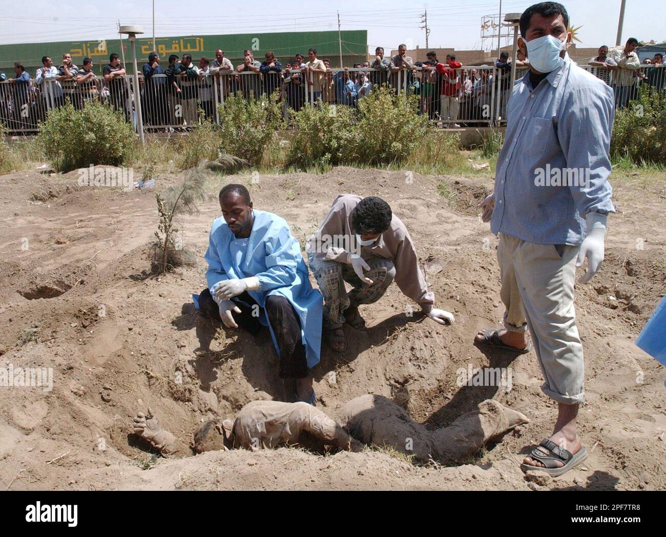 Iraqi doctors and volunteers exhume the body of a man, killed during ...