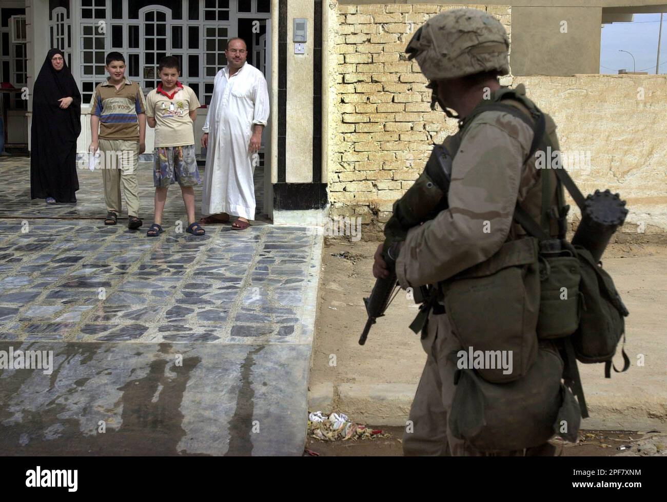 Iraqi civilians stand in their driveway as United States Marines of ...