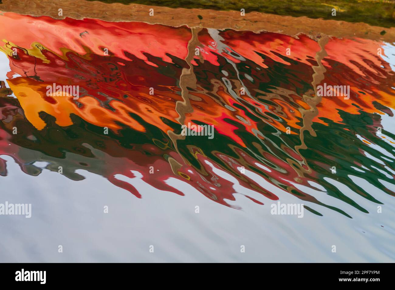 Vivid, bold orange and red abstract reflections of kayaks on a dock in ...