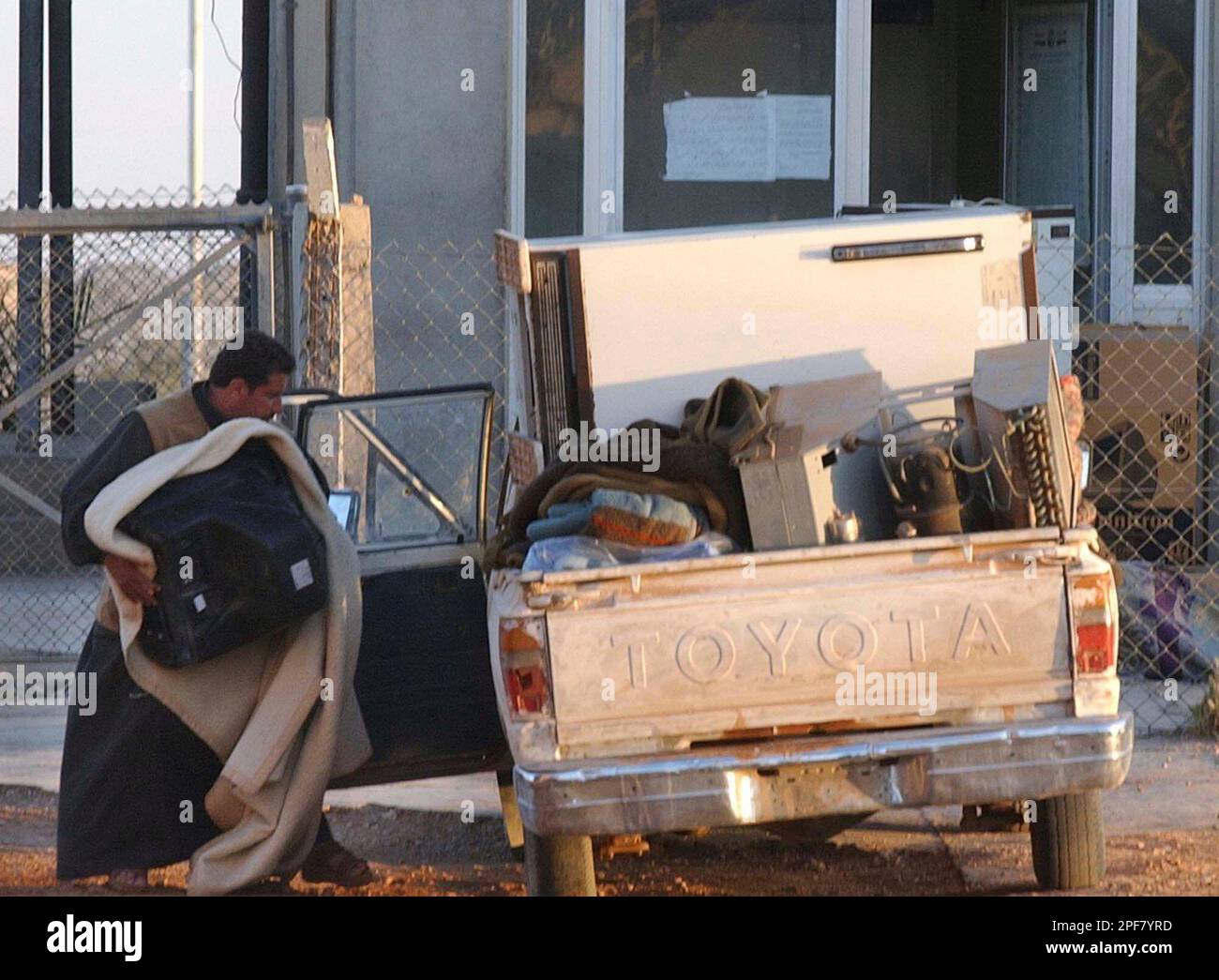 An Iraqi man loots a television from a goverment building at the ...
