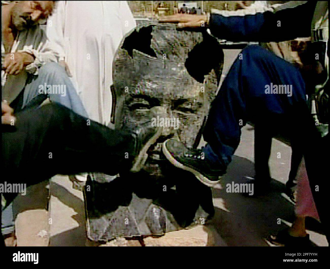Iraqis, seen in this image from video, place their feet on the face of ...