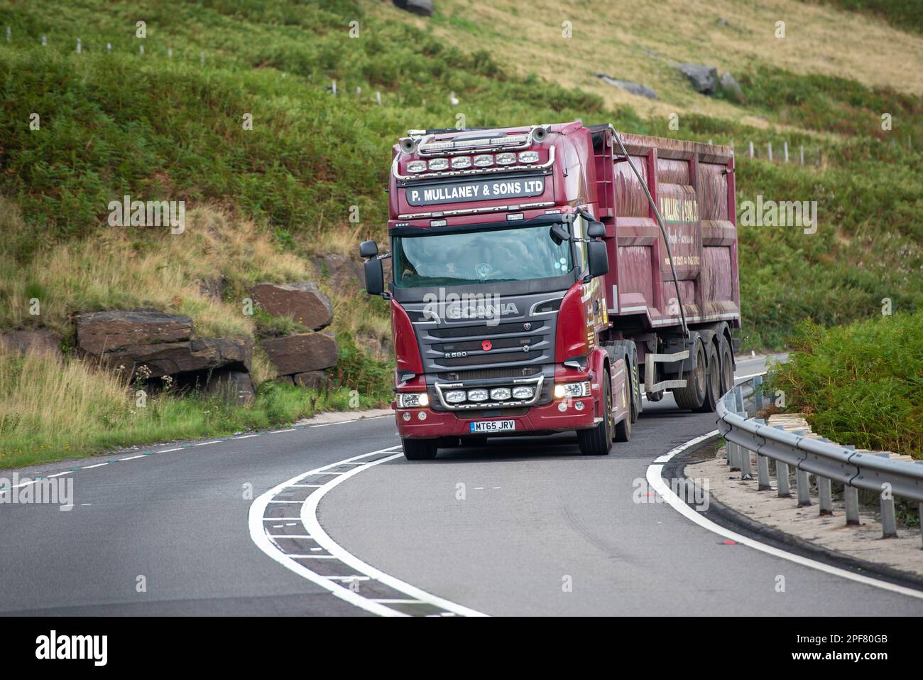 Scania truck pulling a bulk tipper trailer takes a downhill bend on the ...