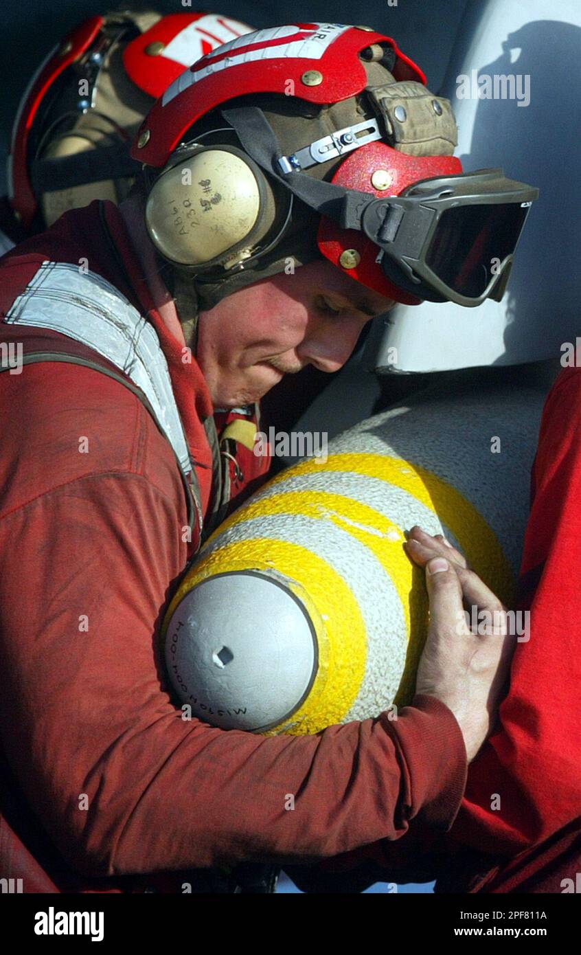 An ordnance specialist loads a 2000 lb. JADM bomb on to an F/A18-Hornet ...