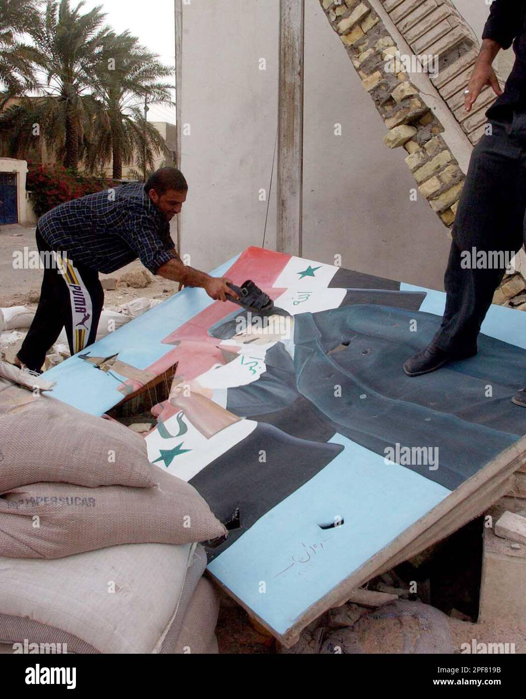 An Iraqi man uses his shoe to smash a hole in the face of a Saddam ...