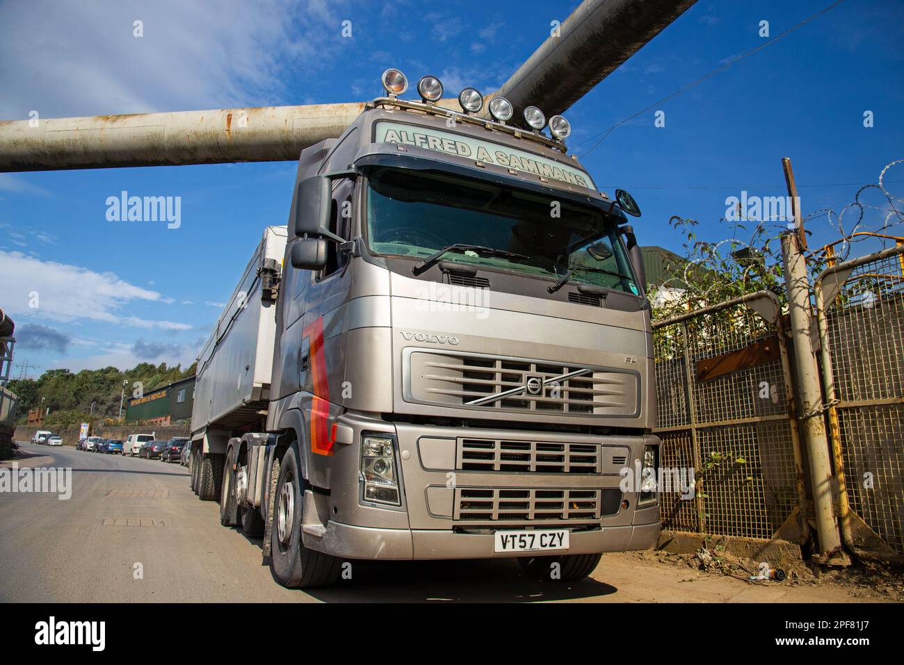 Volvo truck towing a bulk tipper trailer parked near a recycling centre ...