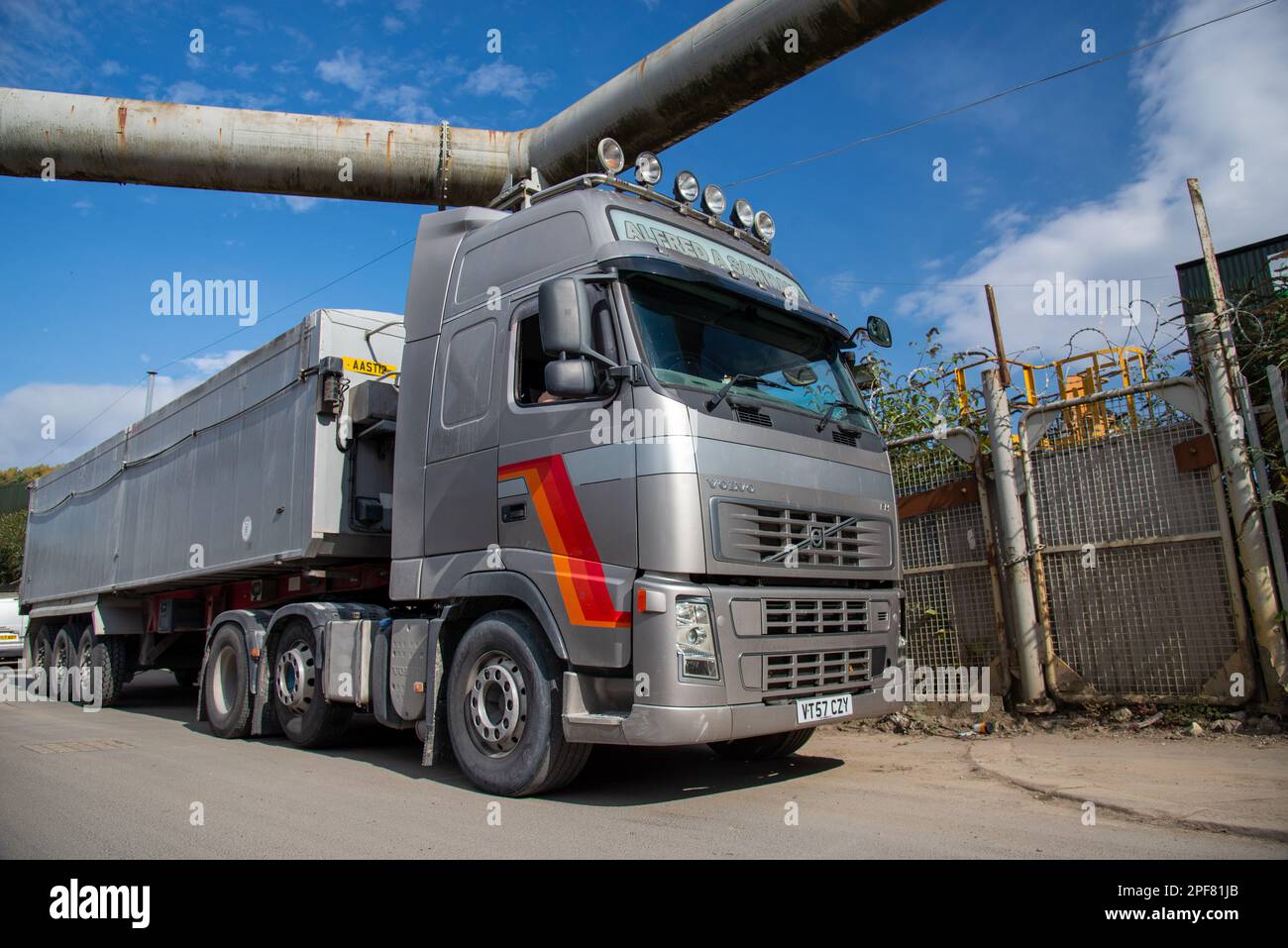 Volvo truck towing a bulk tipper trailer parked near a recycling centre ...
