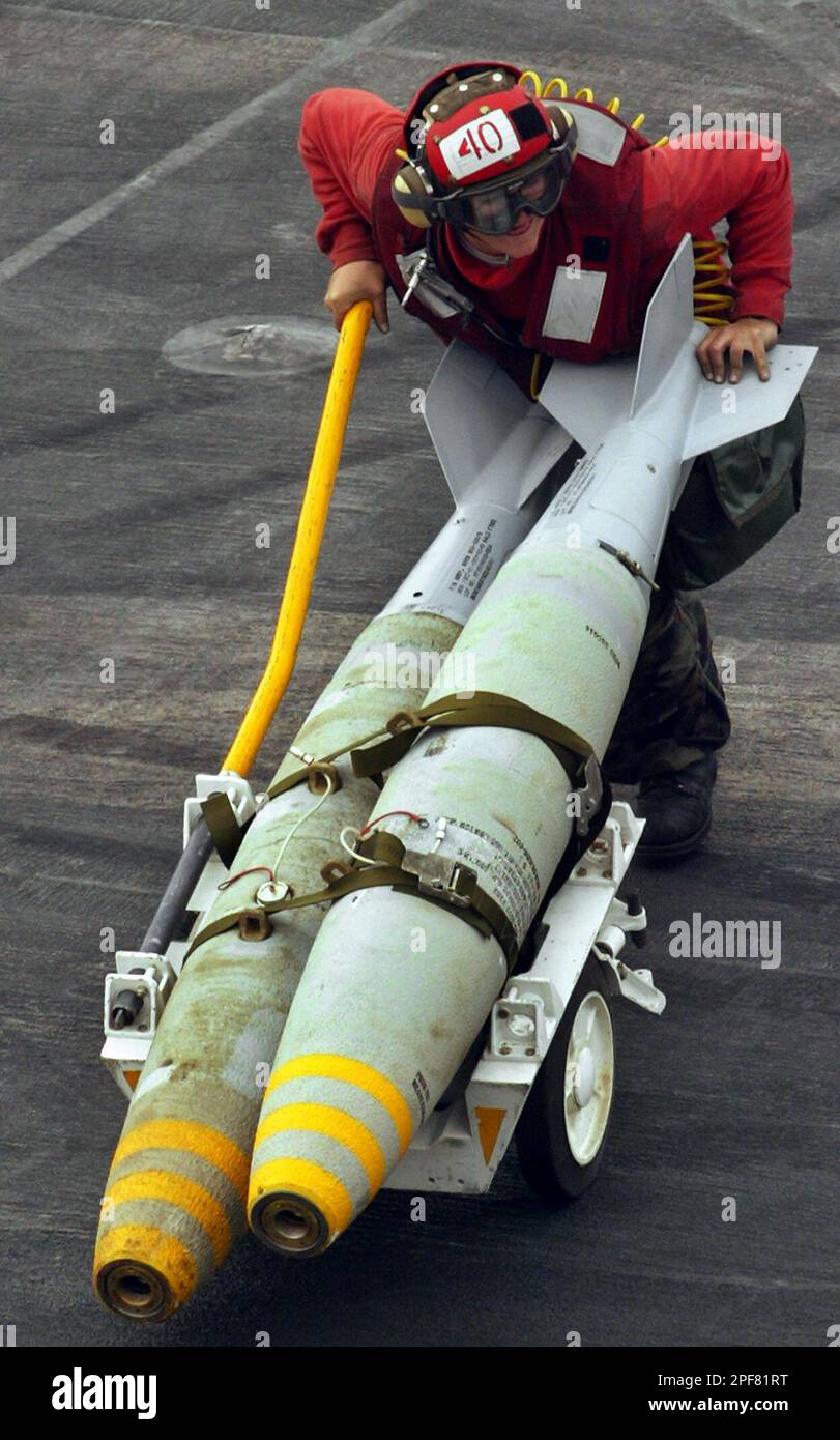 An ordnance specialist pushes Mark-82 bombs along the flight deck of ...