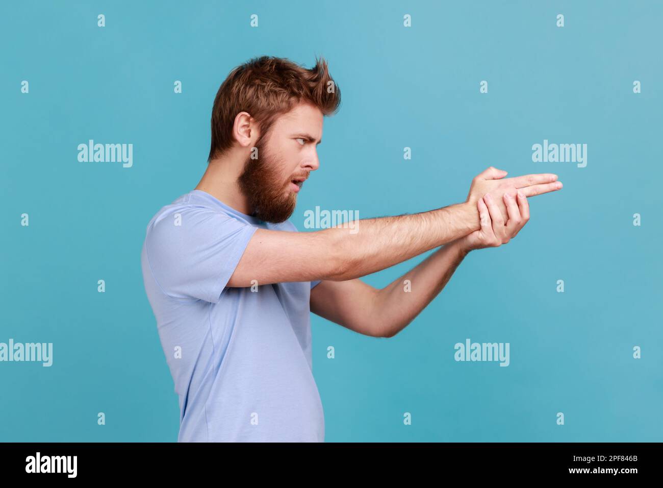 Side view of focused bearded man pointing finger gun gesture to target ...