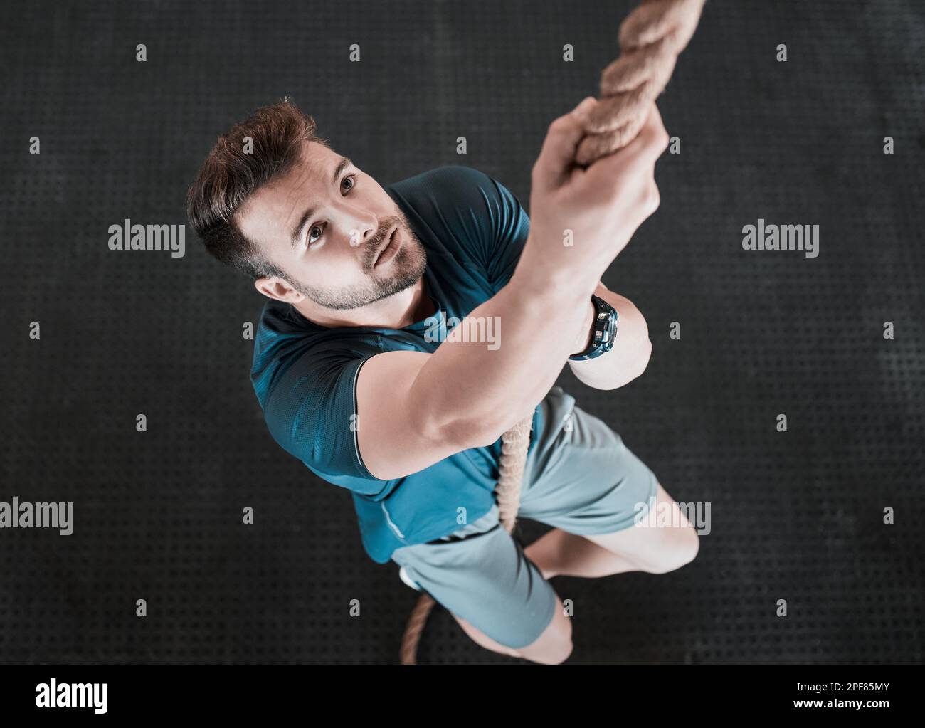 Visualise reaching your goals. a young man climbing a rope in the gym ...