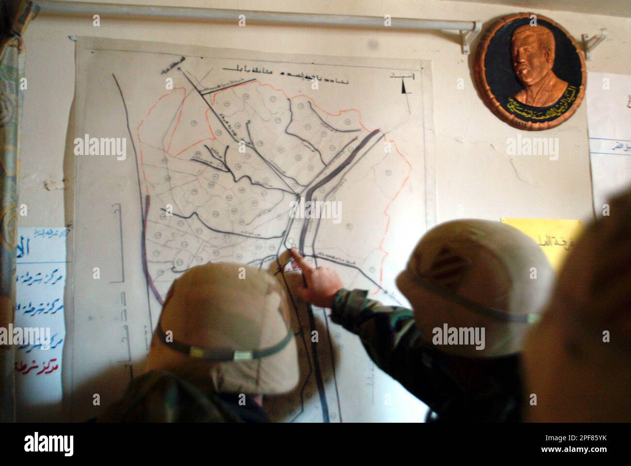 U.S. Army soldiers look over an Iraqi map on the wall of a local police ...