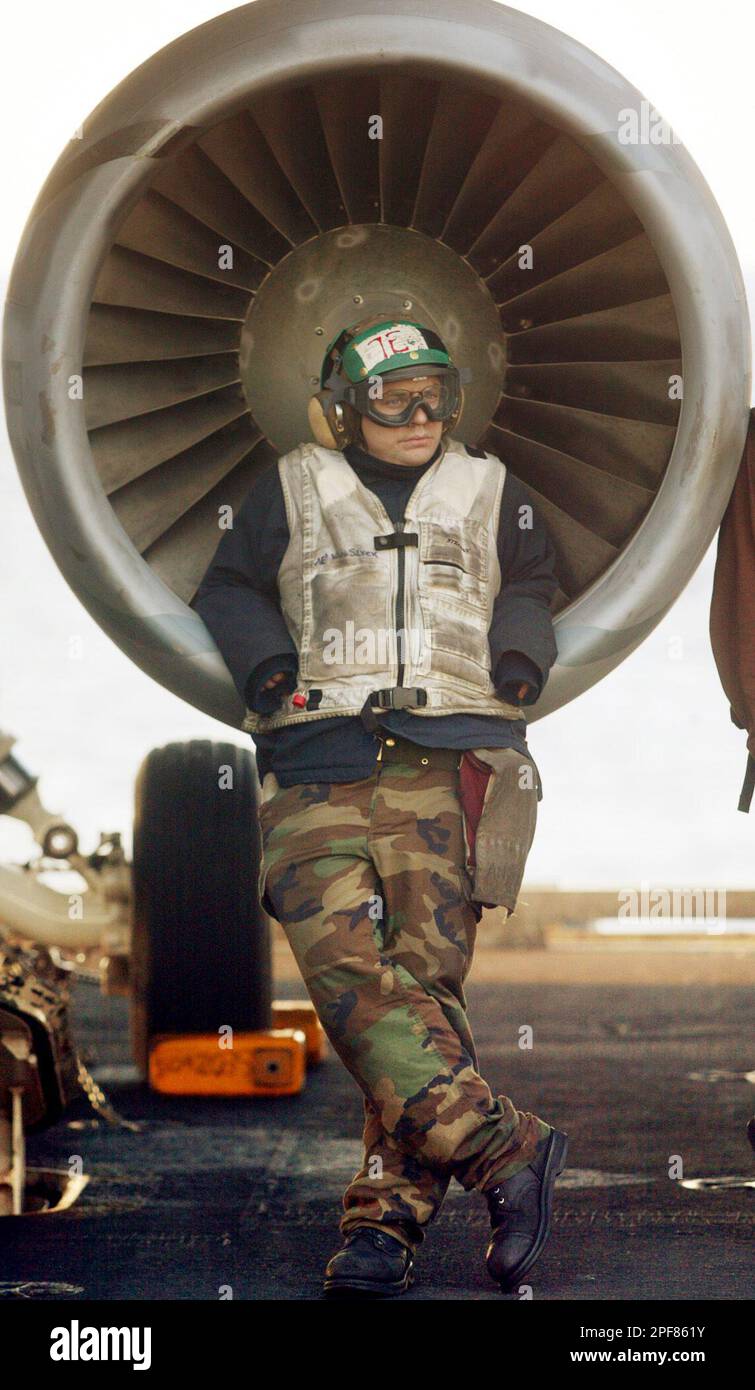A U.S. member of aircraft handling crew leans at the engine of a S-3B ...