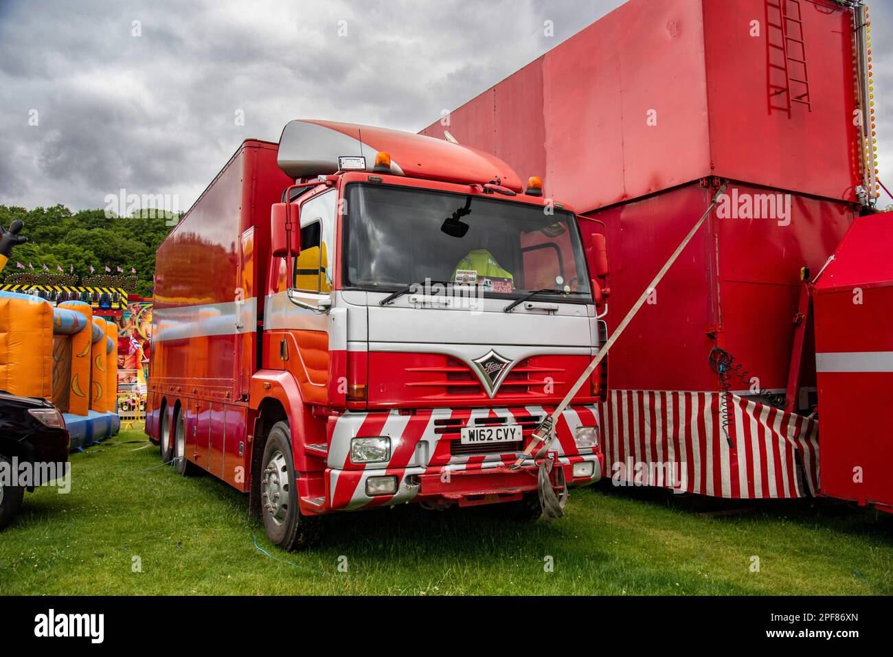 A Foden Alpha generator truck stands behind a fairground ride in a park ...