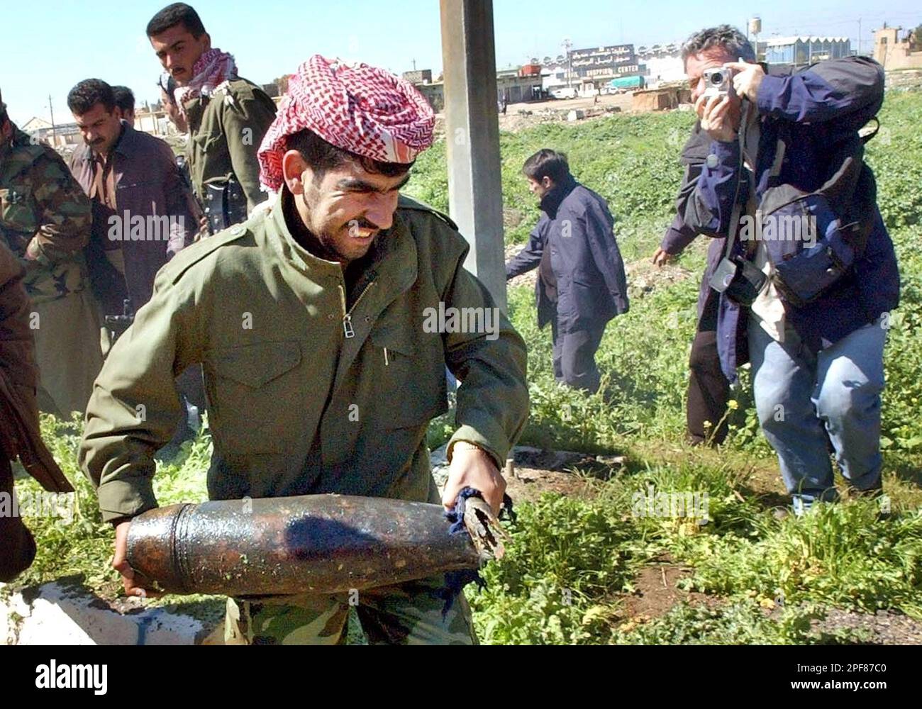 An Iraqi Kurdish militiaman carries parts of an artillery shell that ...
